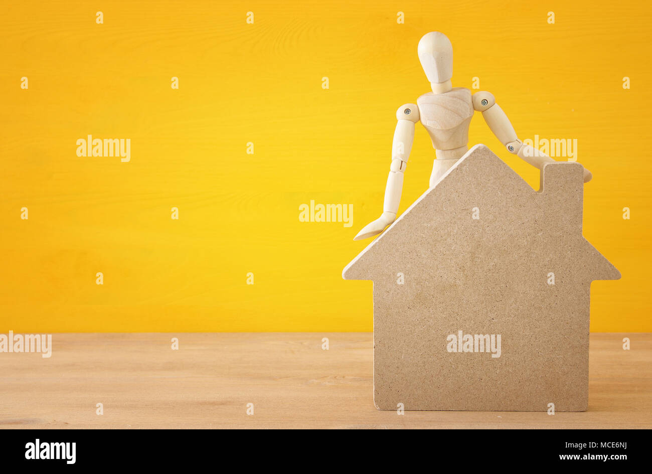 Wooden dummy holding house model. Real estate concept Stock Photo - Alamy