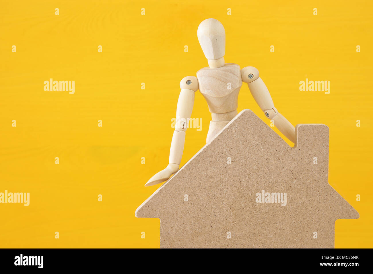 Wooden dummy holding house model. Real estate concept Stock Photo - Alamy
