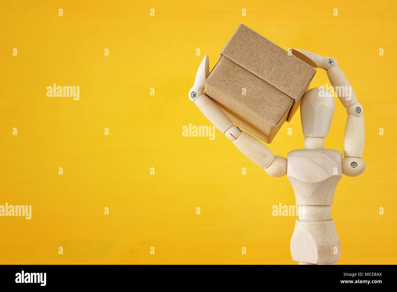 wooden dummy figure holding present box over yellow background Stock ...