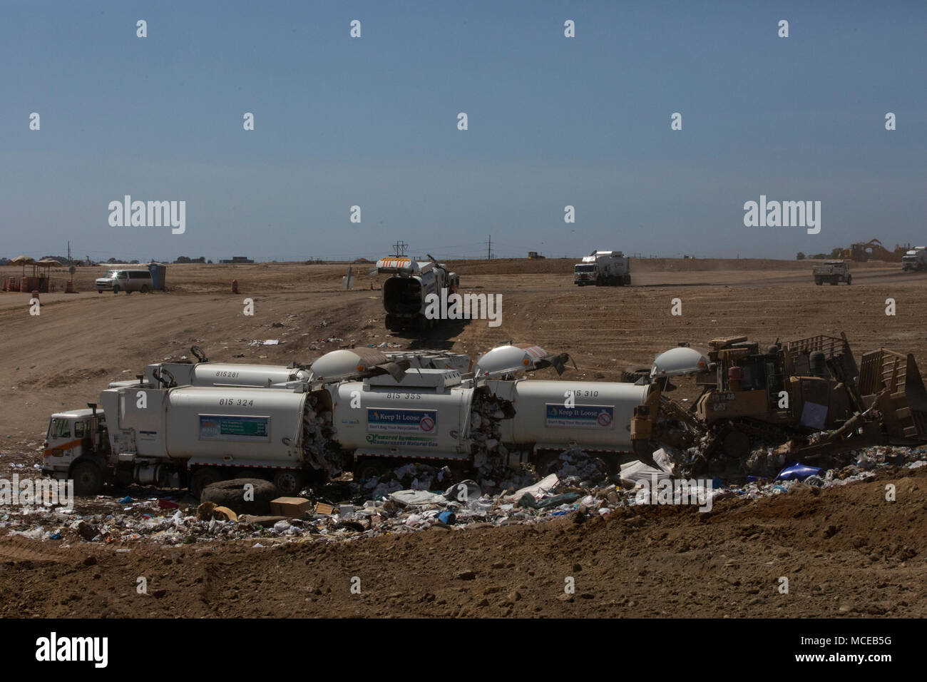 Dump trucks empty trash into a pit where the waste will be converted ...