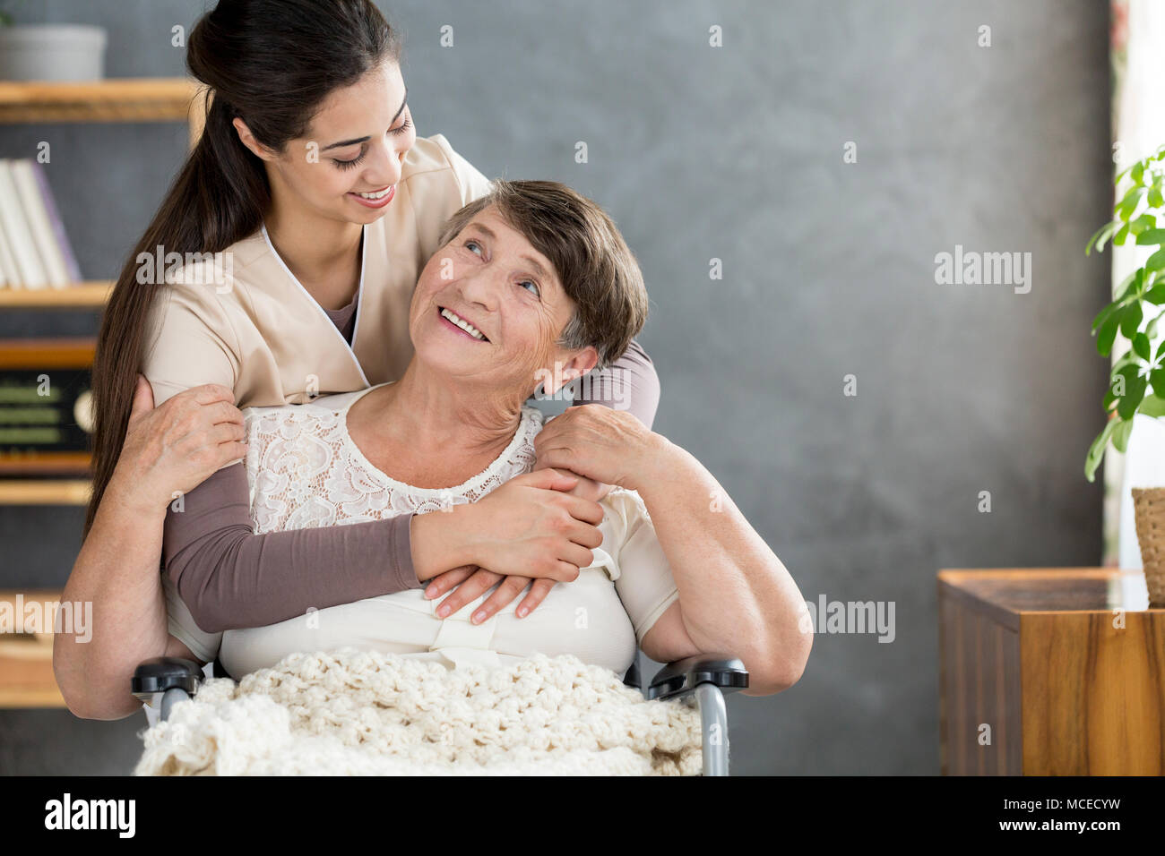 Smiling caregiver hugging her senior patient in a wheelchair Stock ...
