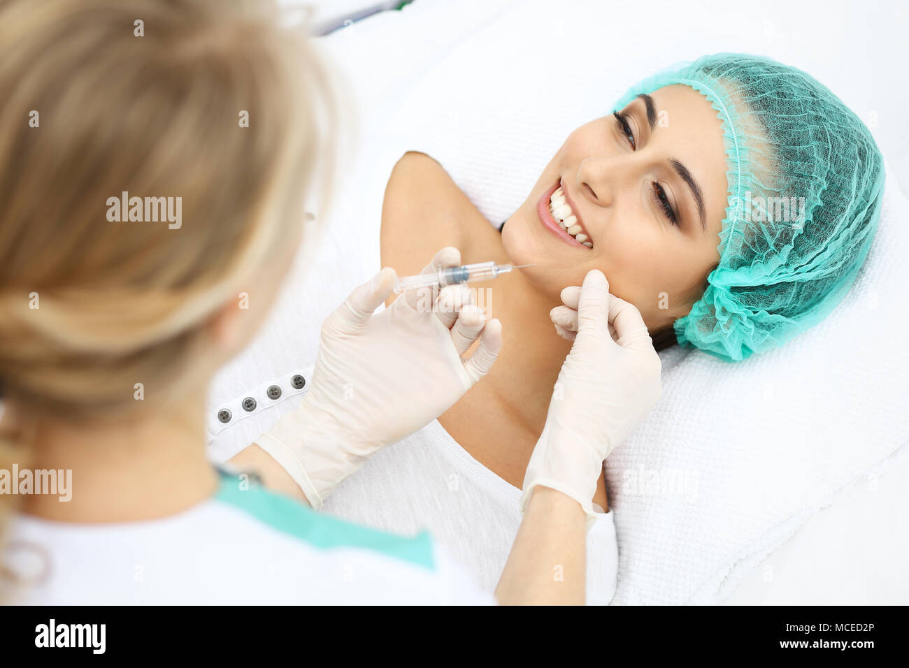 Professional cosmetologist making injection in face, lips. Young woman ...