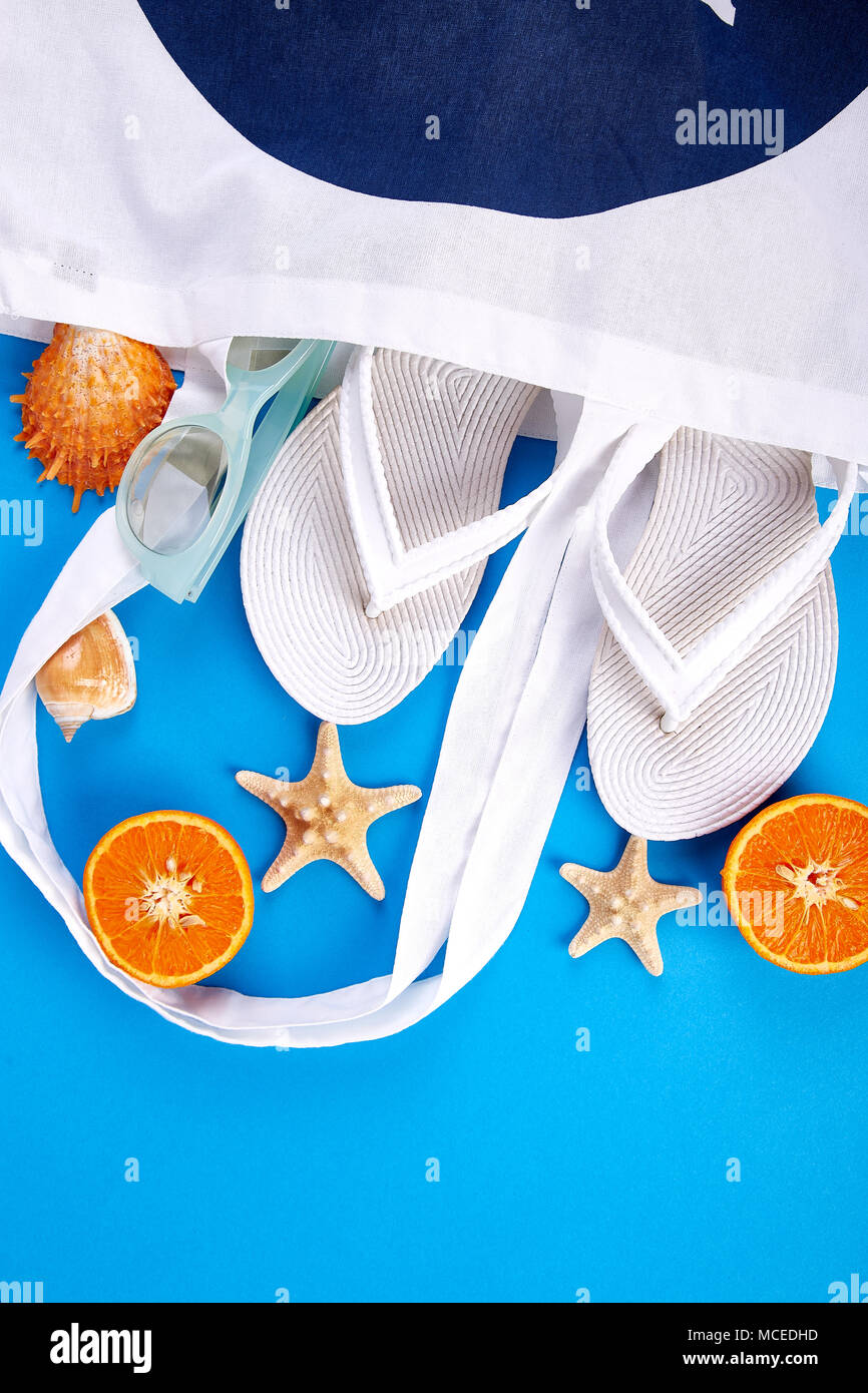 Summer beach bag with white flip flops, sunglasses, seashells, orange ...