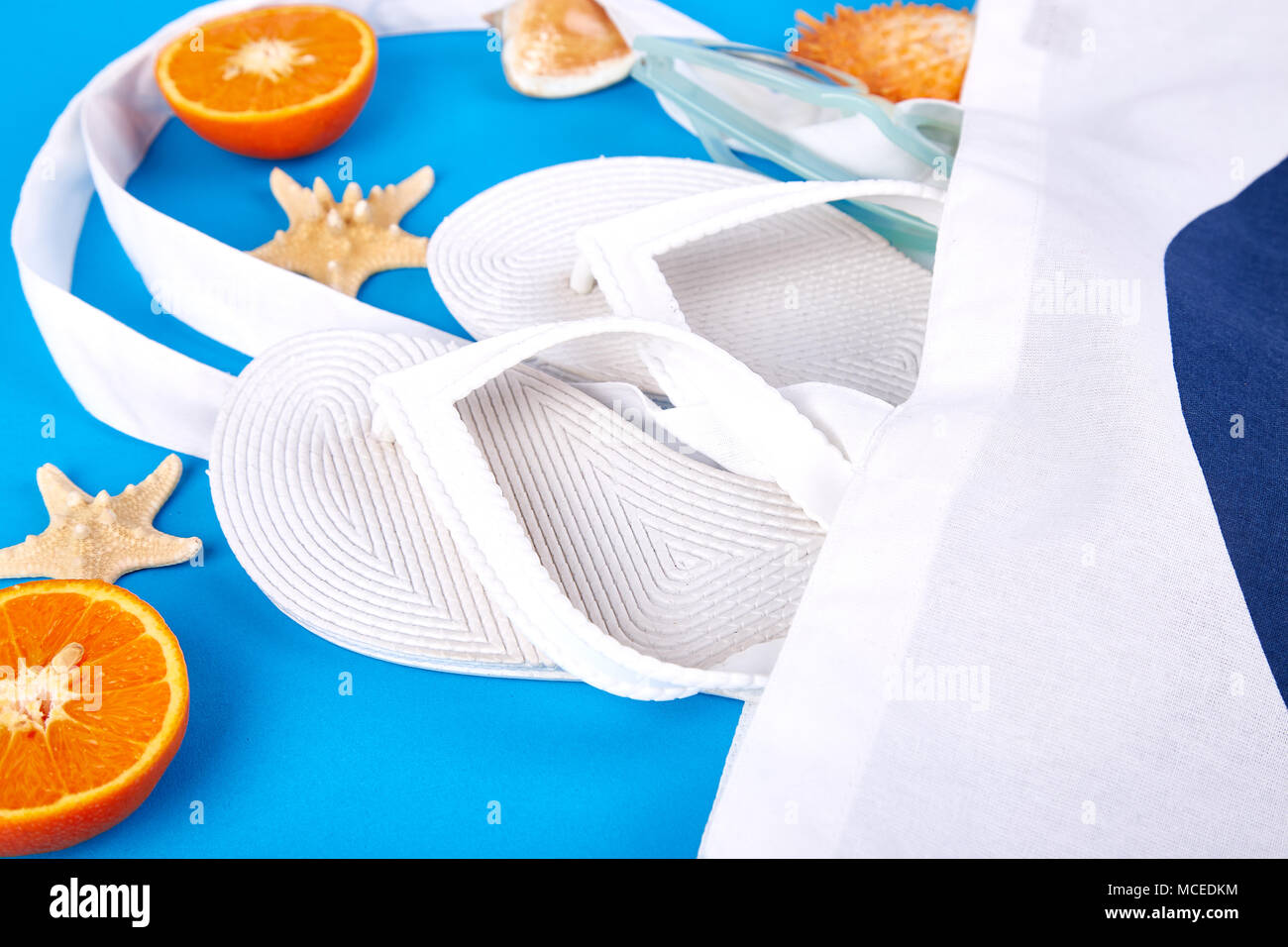Summer beach bag with white flip flops, sunglasses, seashells, orange ...