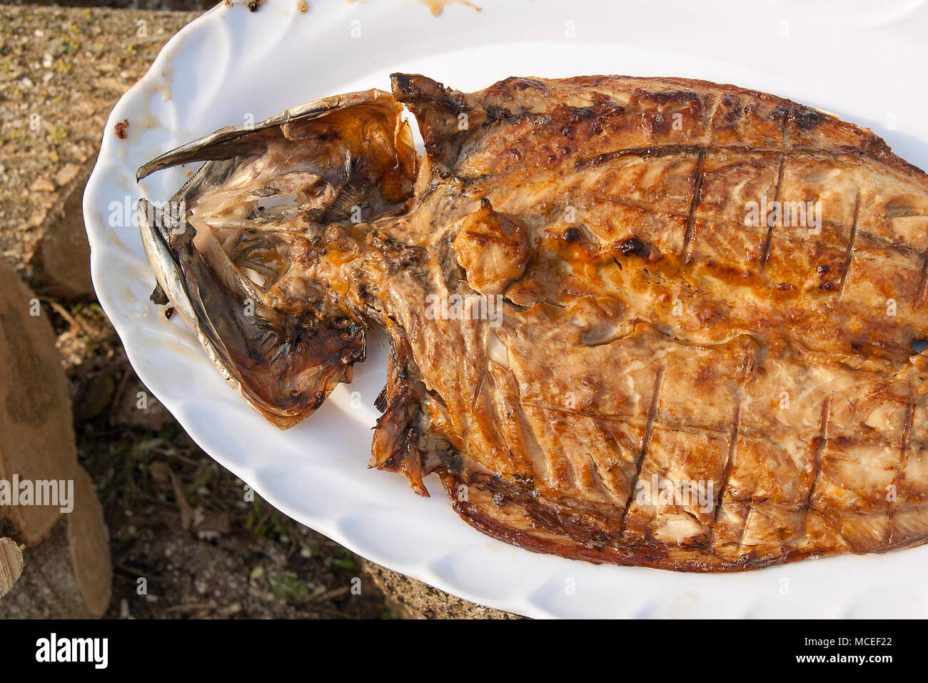 Close up view of fresh fish with sauce cooked on an open flame grill on ...
