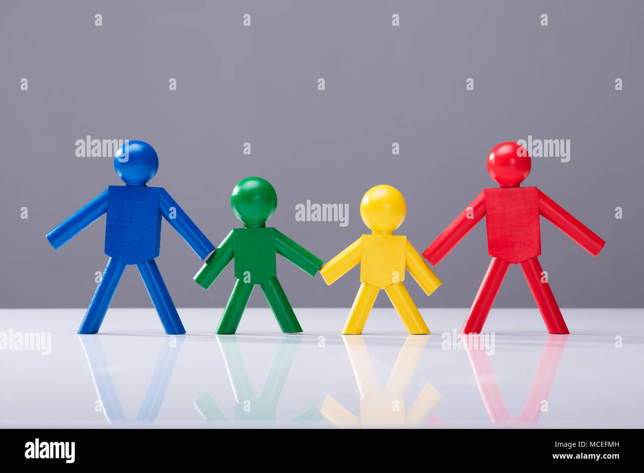 Multi Colored Human Figures Standing Together In A Row On White Desk ...