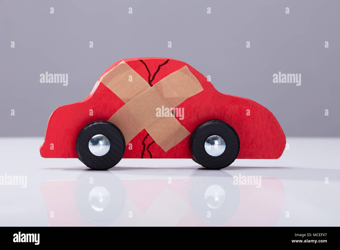 Broken Red Car With Cross Band Aid Against Grey Background Stock Photo ...