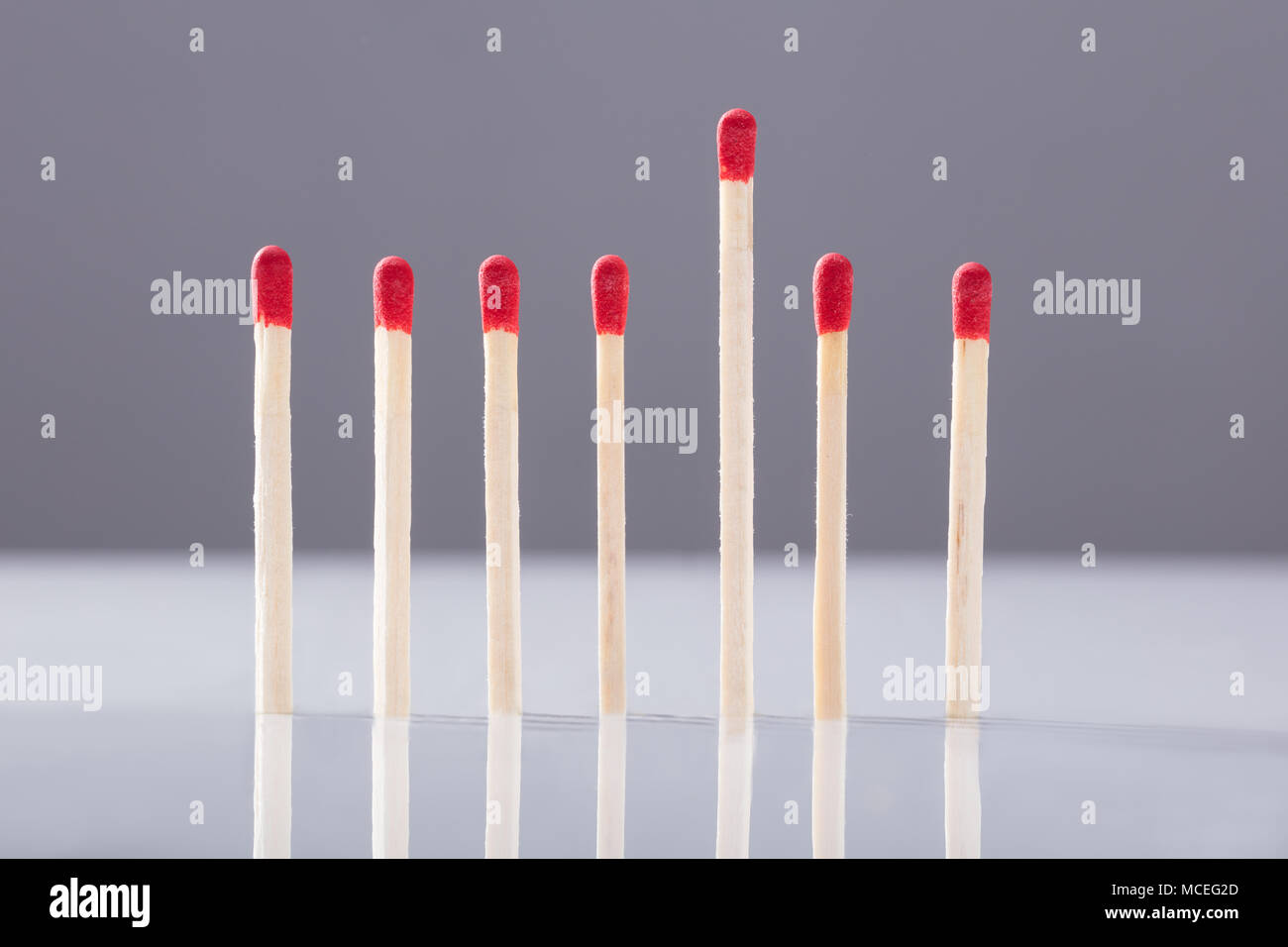 Raised Up Stick Among Unused Matchstick In A Row Against Grey ...