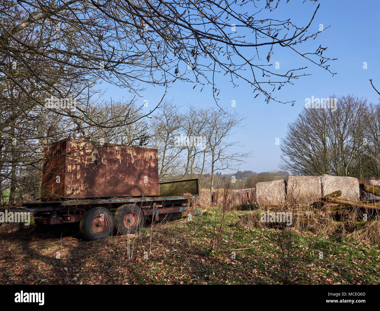 An abandoned Farm Trailer and Tank lie in a corner of a Field alongside ...