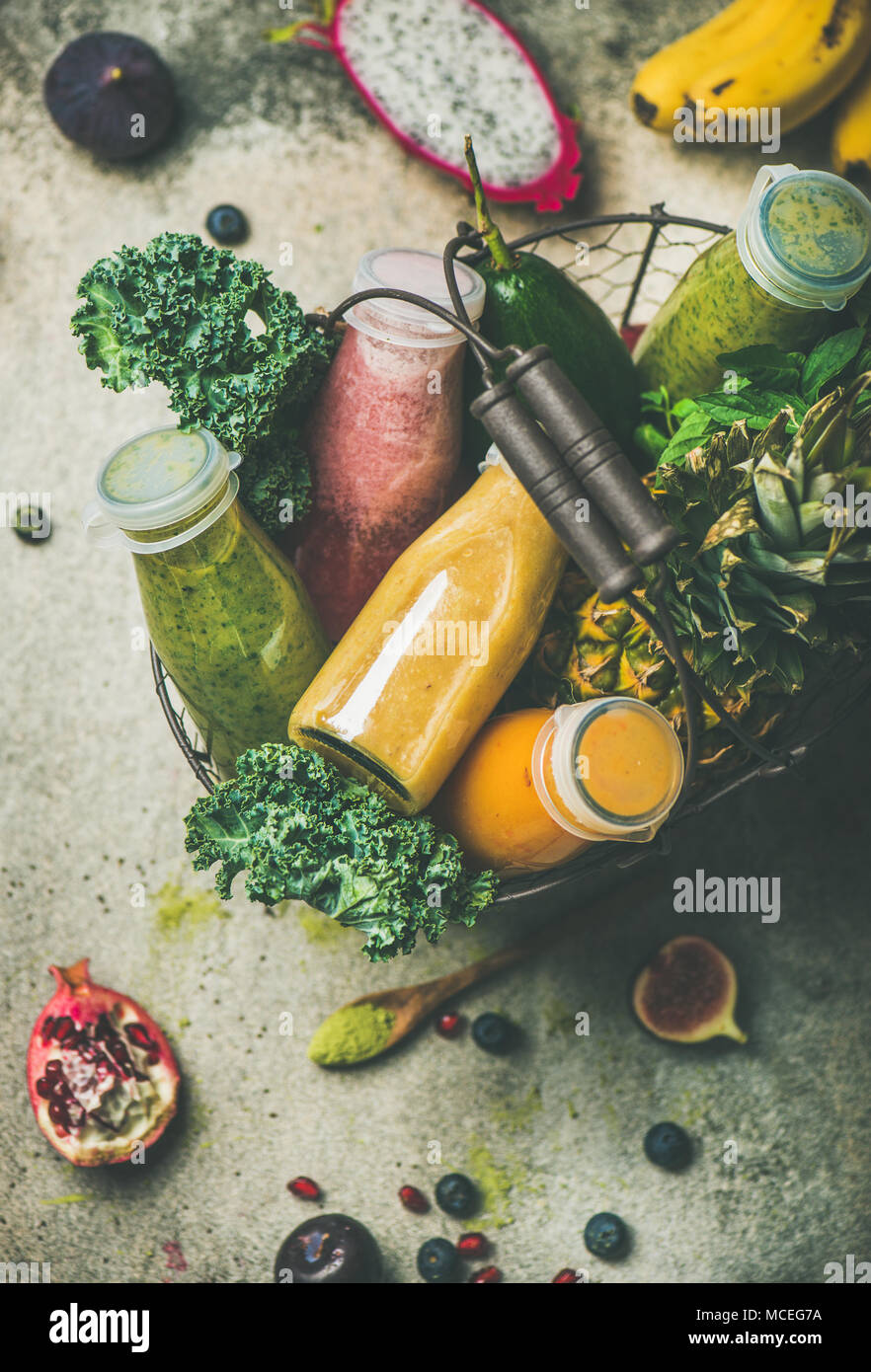 Colorful smoothies in bottles with fruits in basket, grey background ...