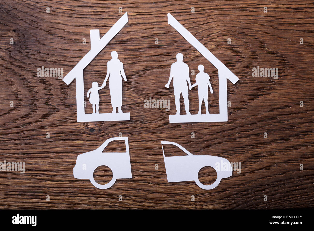 White Paper Cutout Of A Family Split Apart With Car On Wooden ...