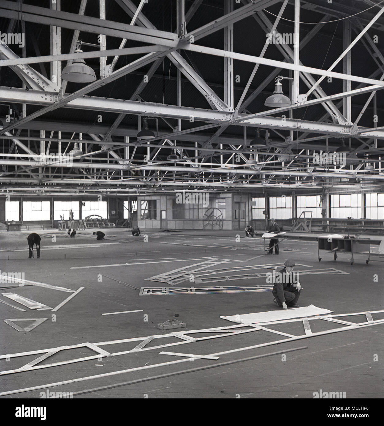 1950s, historical, workers in a large low-level aviation hangar at the ...