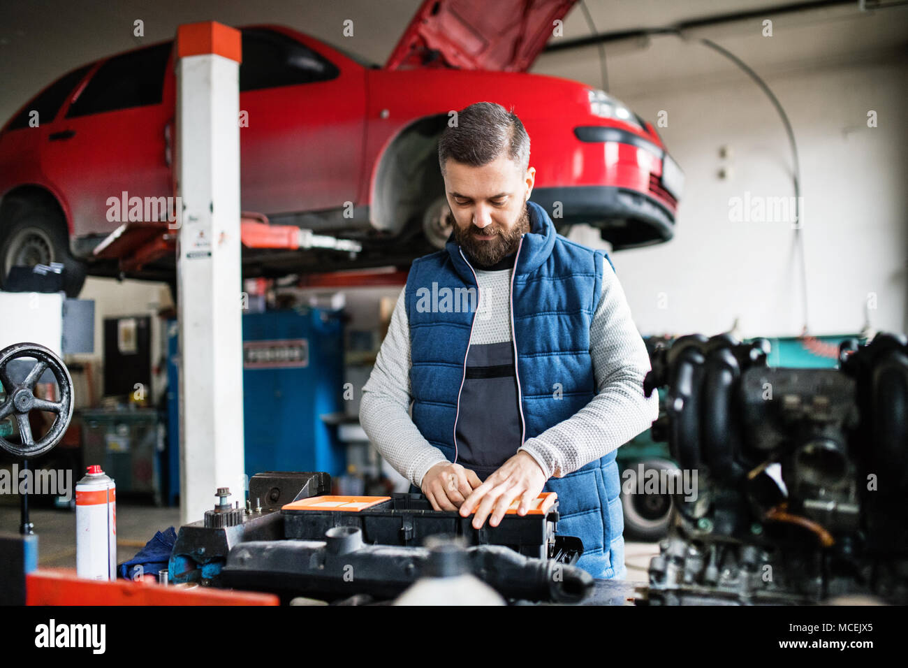 Man mechanic repairing a car in a garage Stock Photo - Alamy