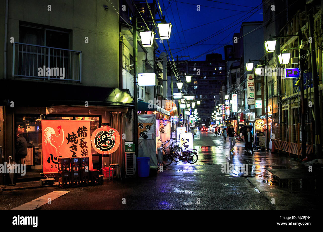 Osaka, Japan - April 14, 2018: Lights reflect off a quiet street after ...