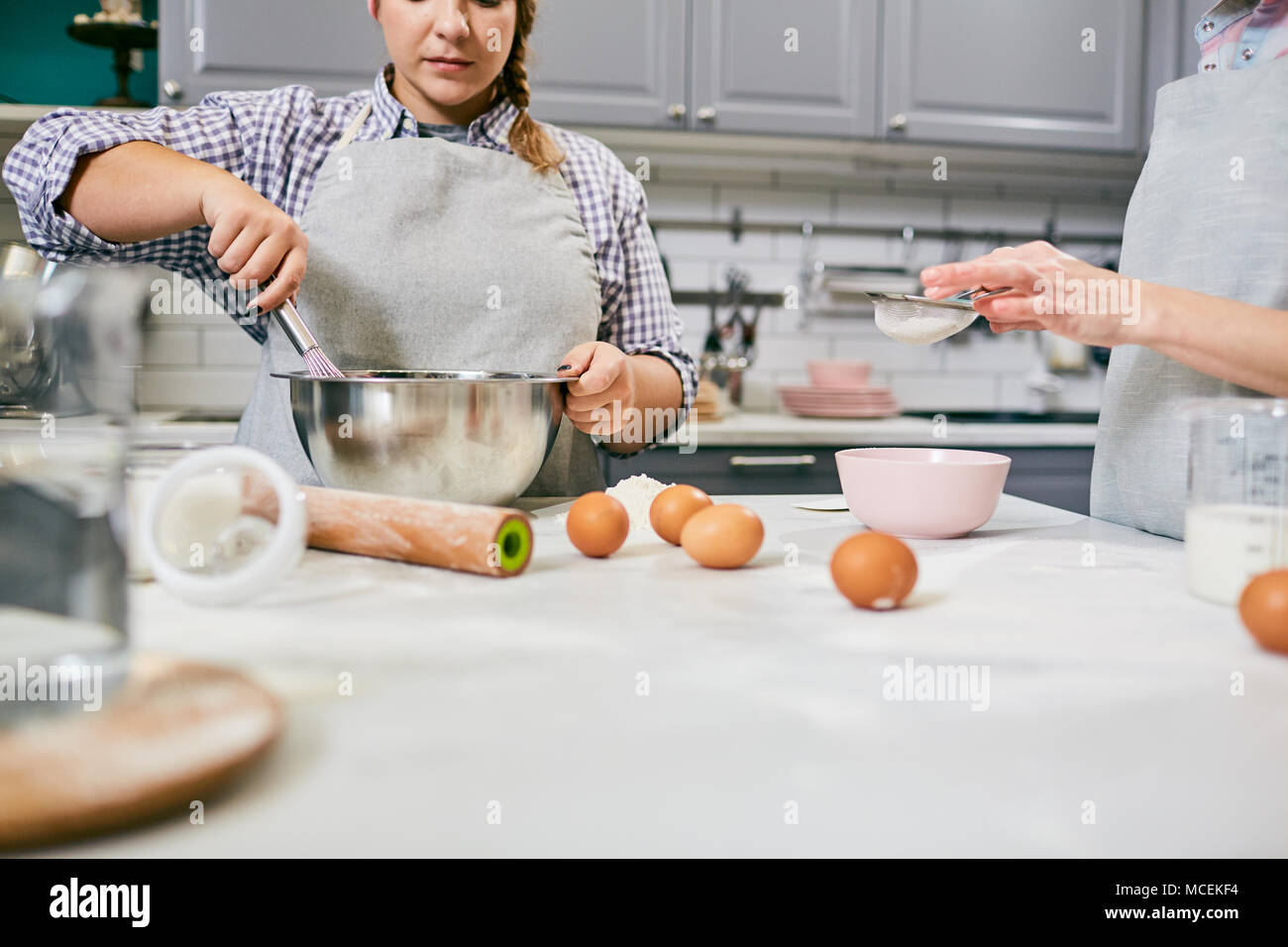 Low angle view of young female cook and her unrecognizable colleague ...