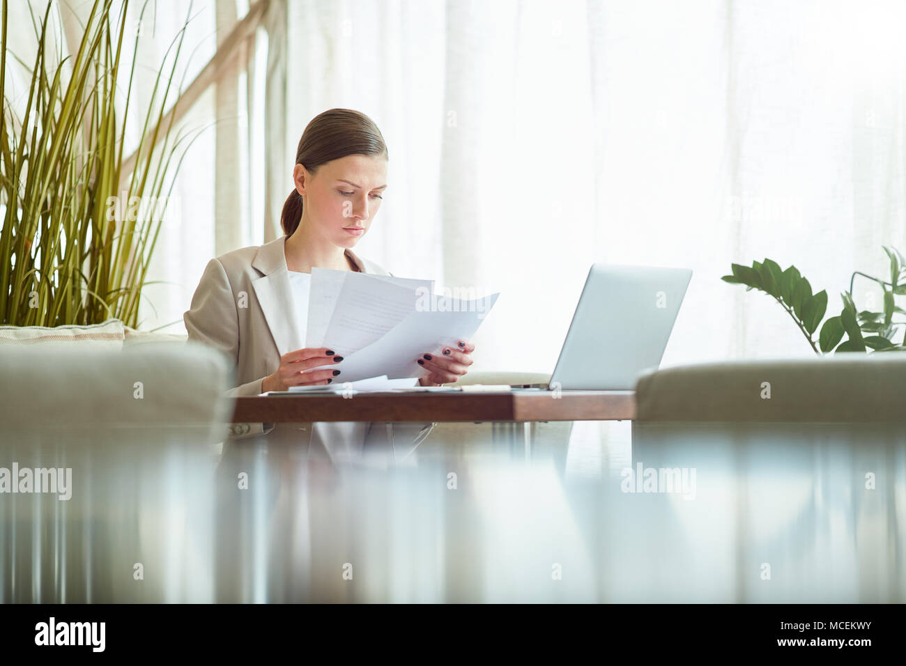 Young attractive Caucasian woman in formal wear looking through ...