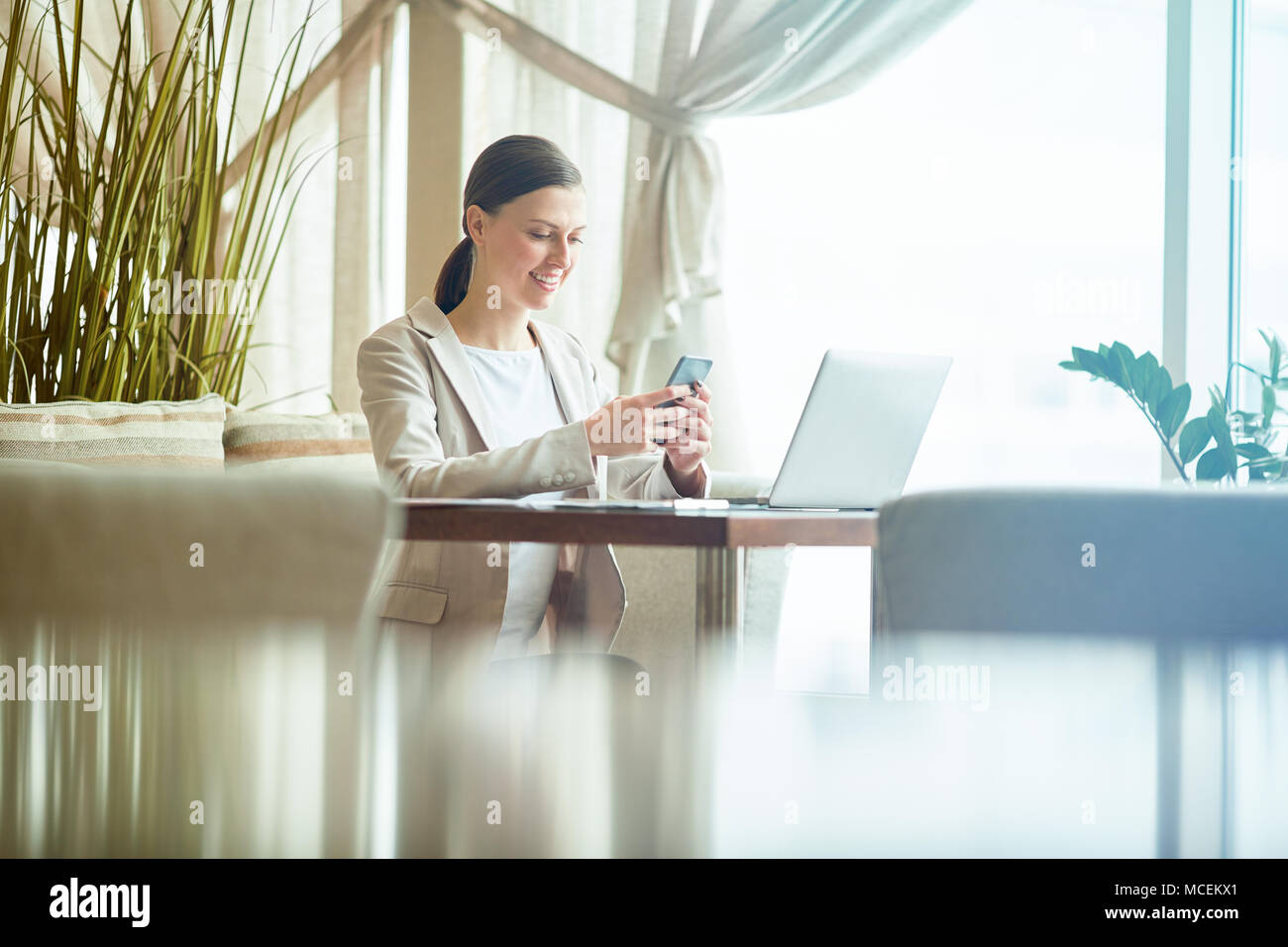 Young attractive woman in elegant business suit texting on smartphone ...