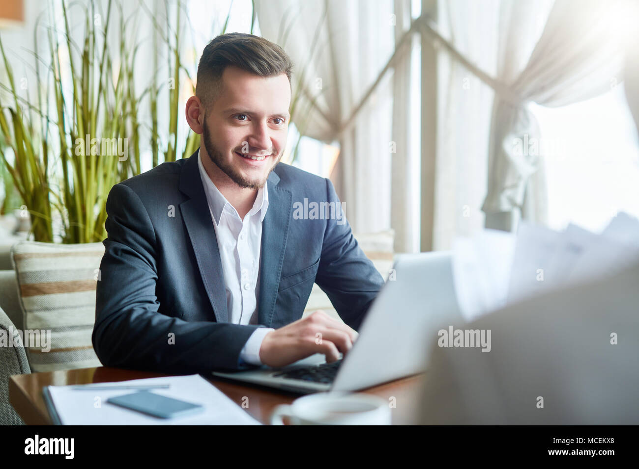 Young Caucasian male manager working on laptop, listening to his ...
