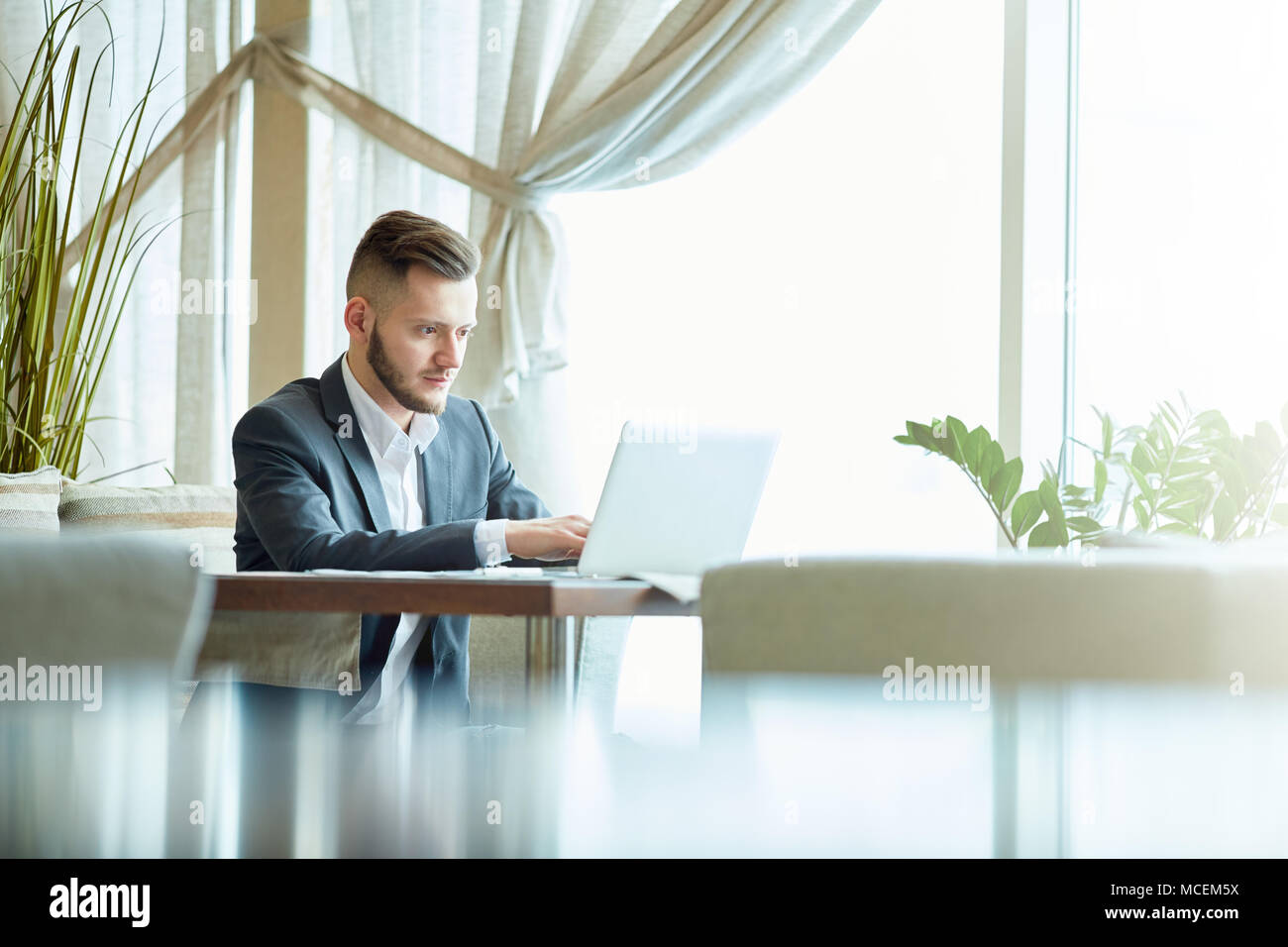 Confident attractive Caucasian man in business suit working on notebook ...
