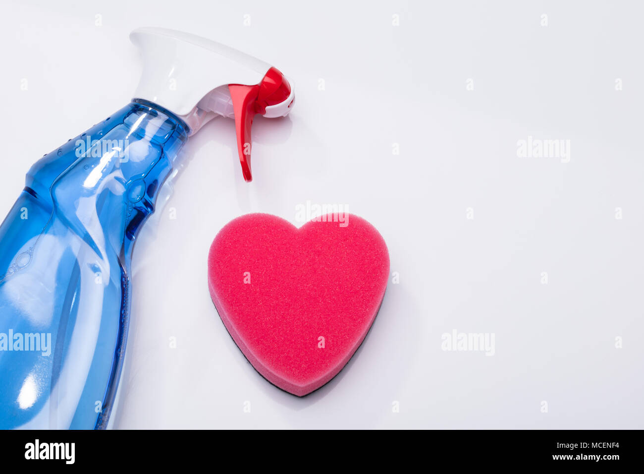 Pink Soft Heart Shape Sponge And Blue Cleaning Spray Bottle On White ...