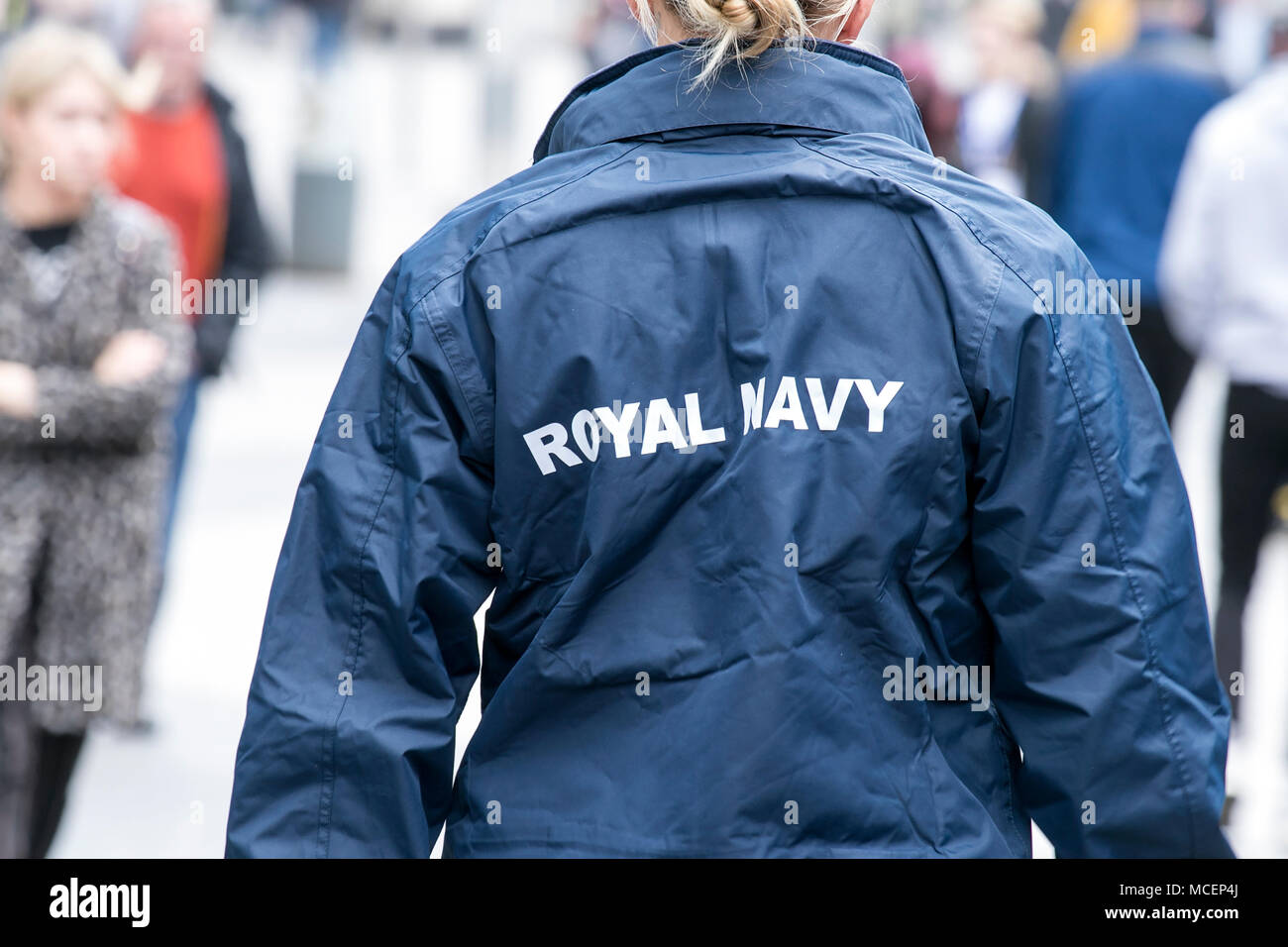 A female Royal Navy sailor wearing uniform with blue logo from rear ...