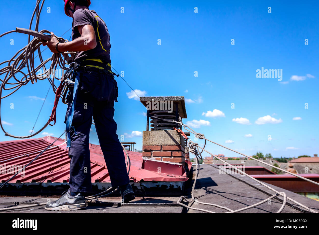 Industrial climber, alpinist, is adjusting climbing gear, preparing ...