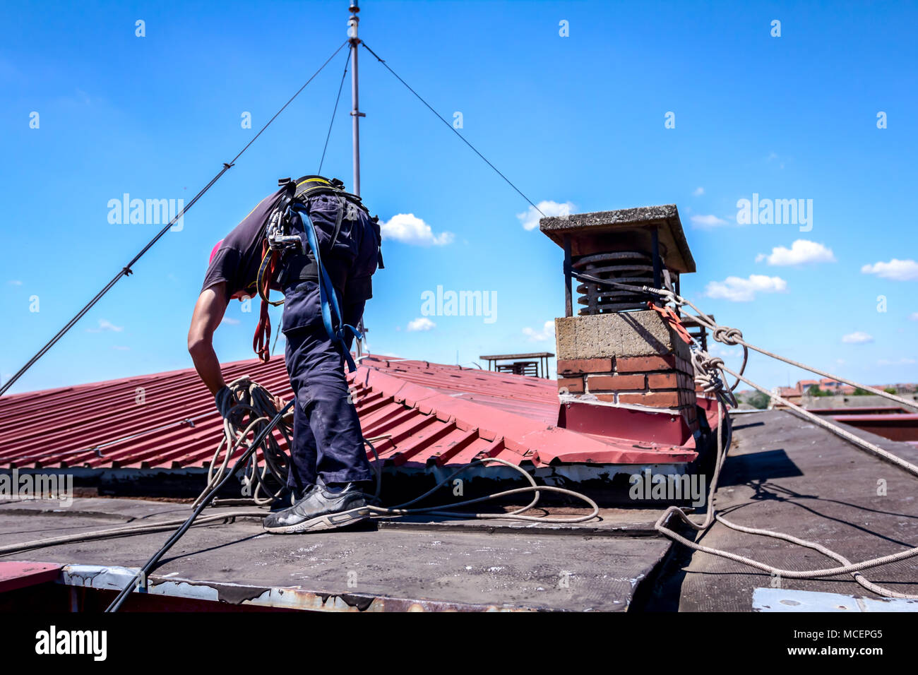 Industrial climber, alpinist, is adjusting climbing gear, preparing ...