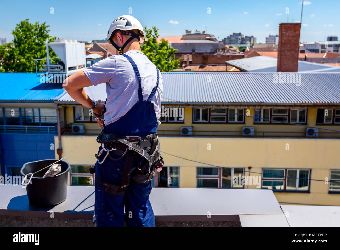 Industrial climber, alpinist, is adjusting climbing gear, preparing ...