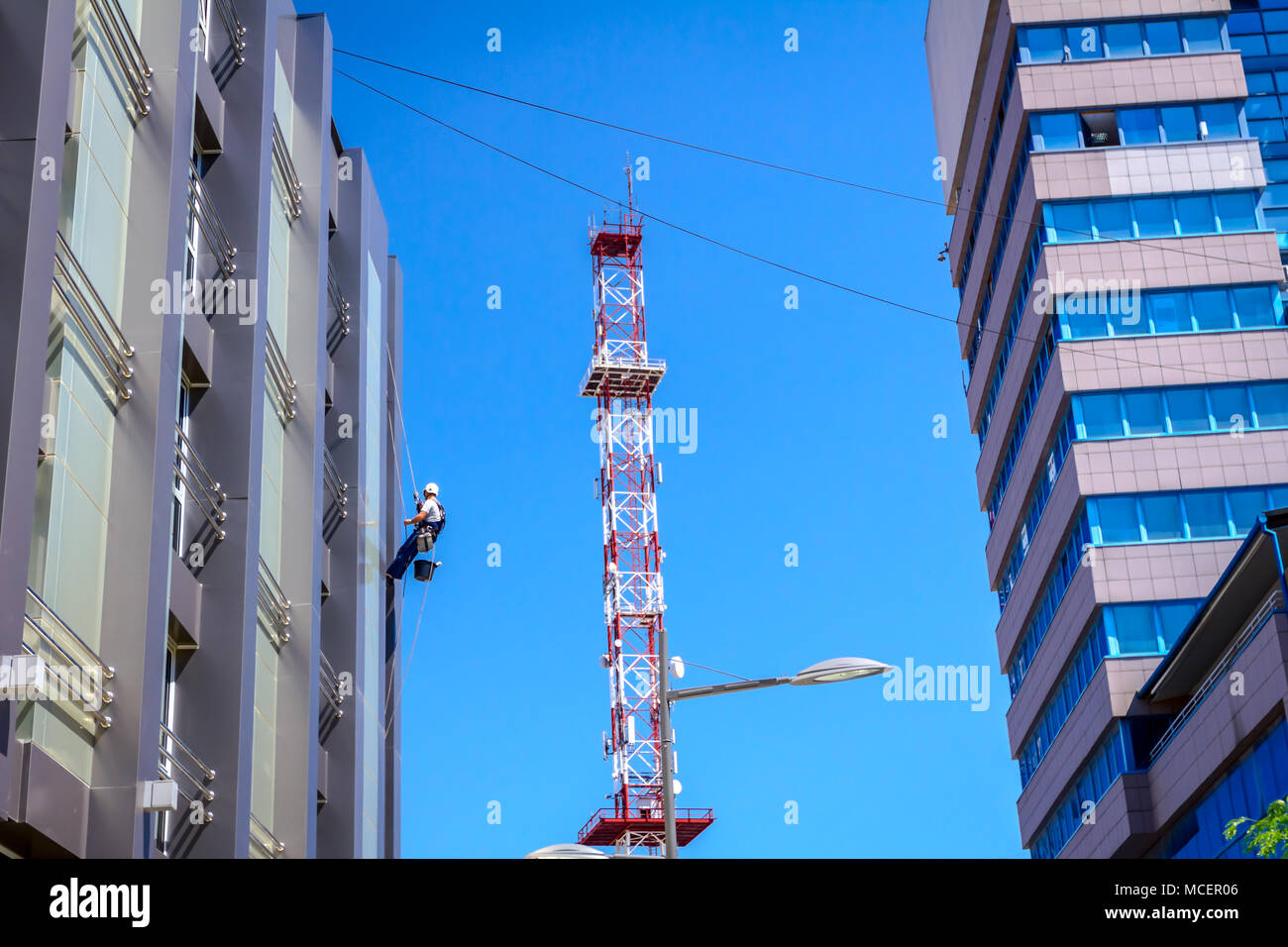 View from below on young man, industrial climber at work, he washing ...