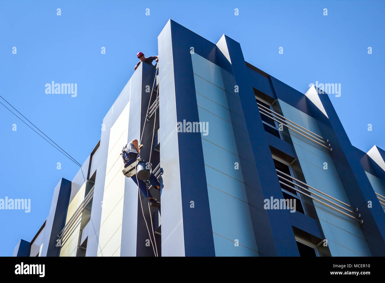 View from below on young man, industrial climber at work, he washing ...