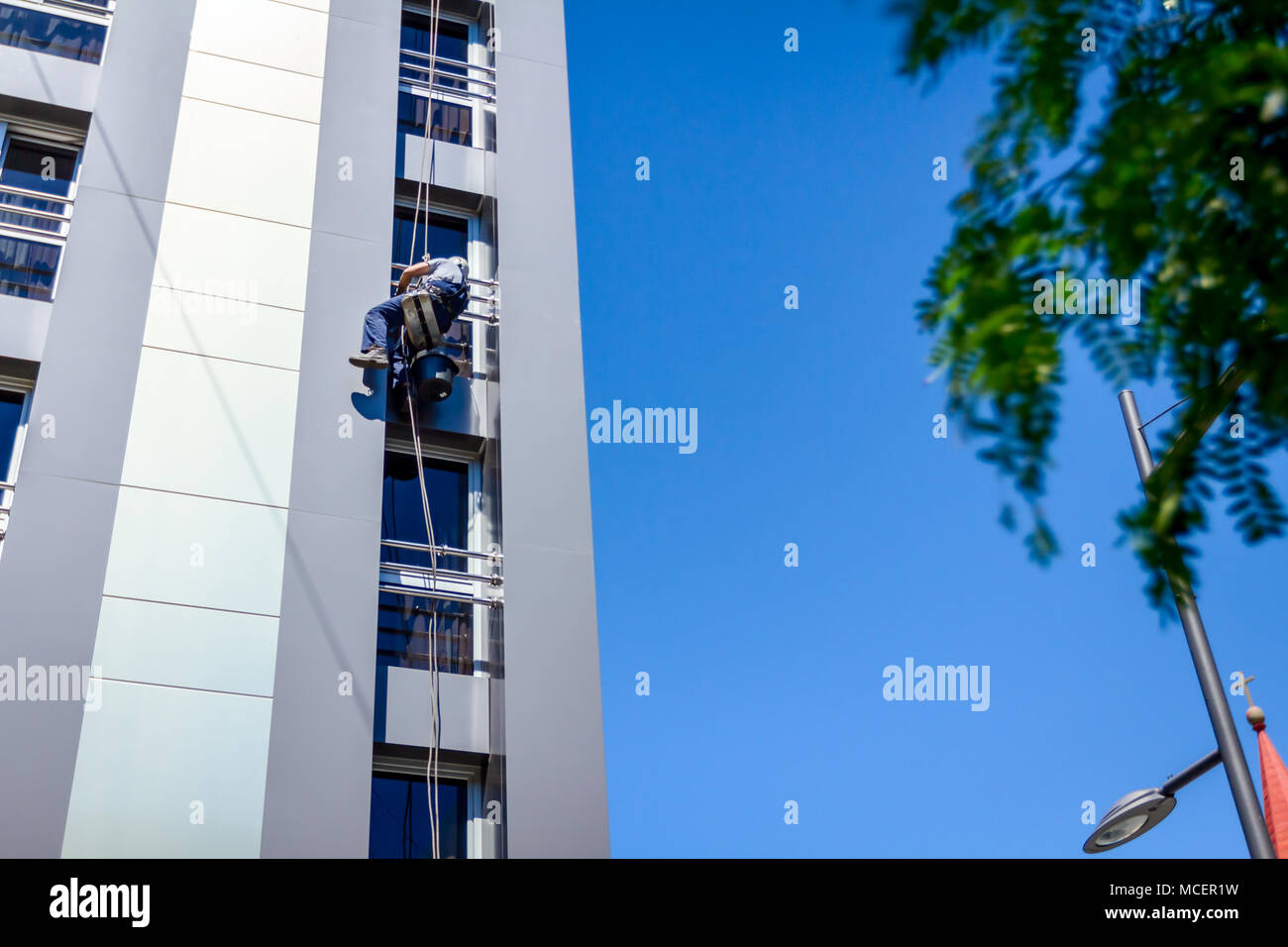 View from below on young man, industrial climber at work, he washing ...