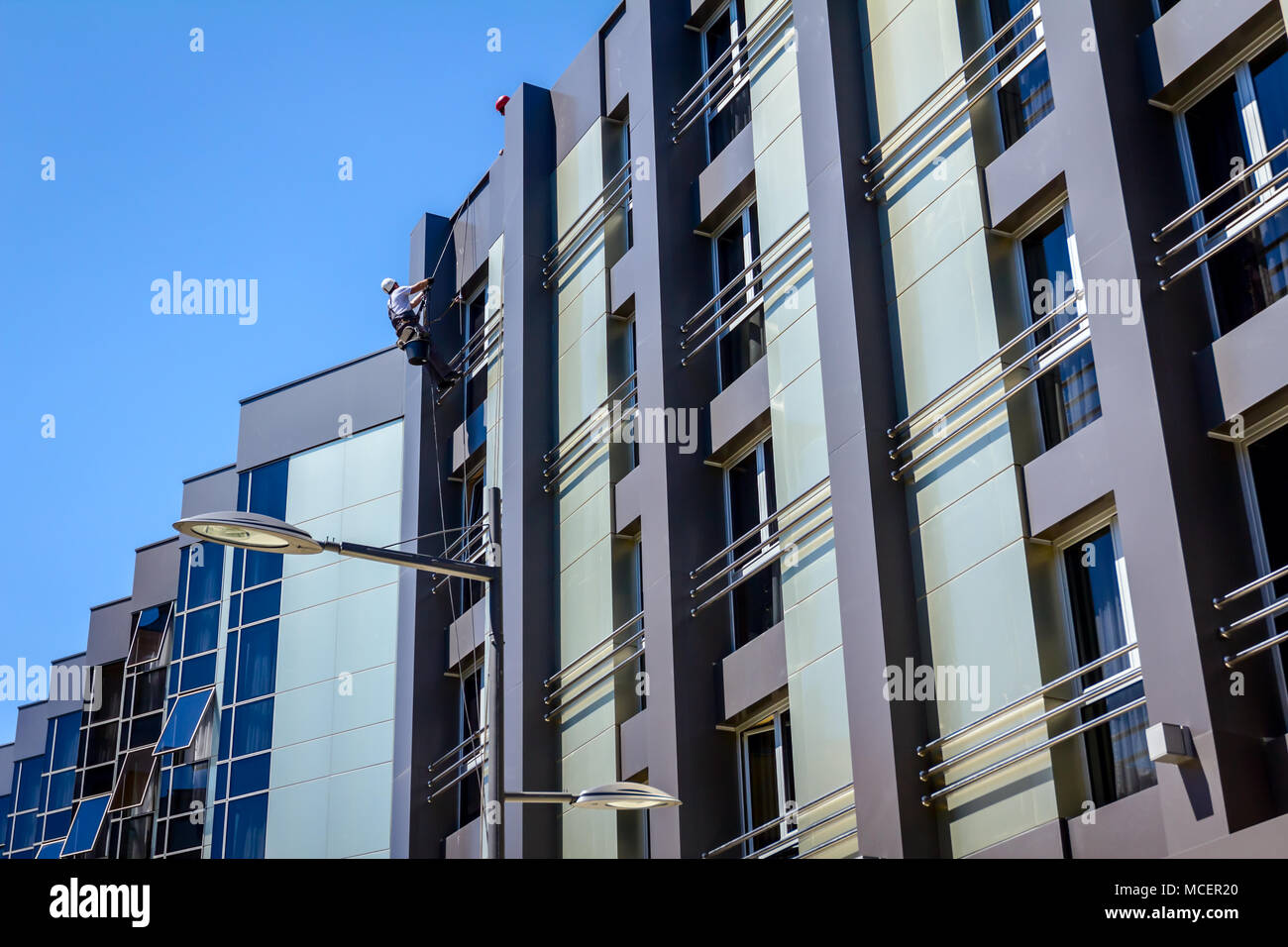 View from below on young man, industrial climber at work, he washing ...