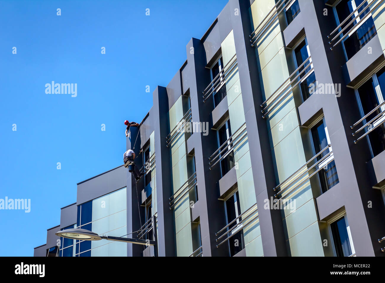 View from below on young man, industrial climber at work, he washing ...