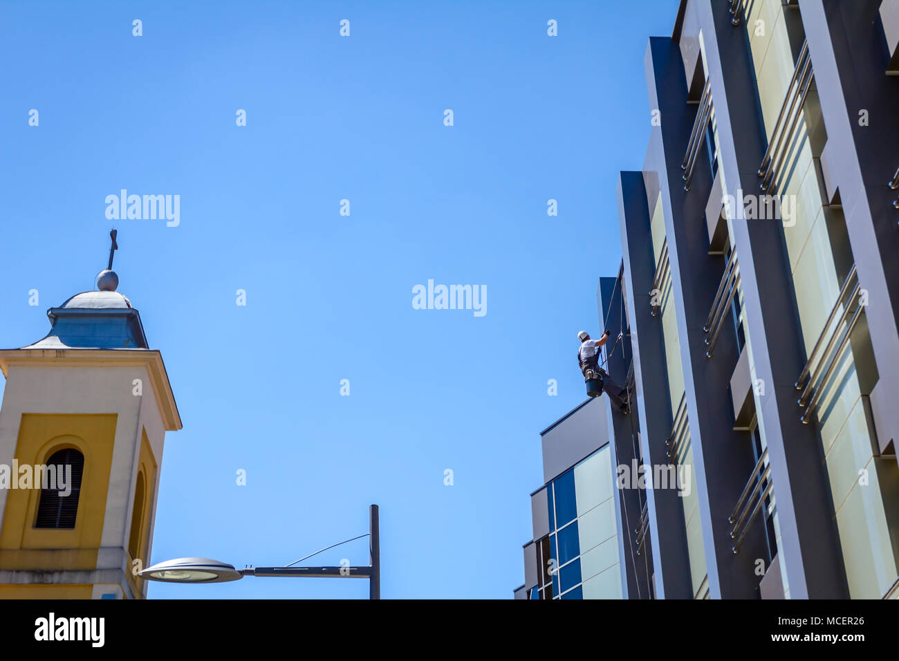 View from below on young man, industrial climber at work, he washing ...