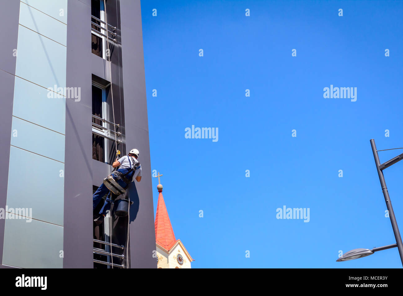 View from below on young man, industrial climber at work, he washing ...