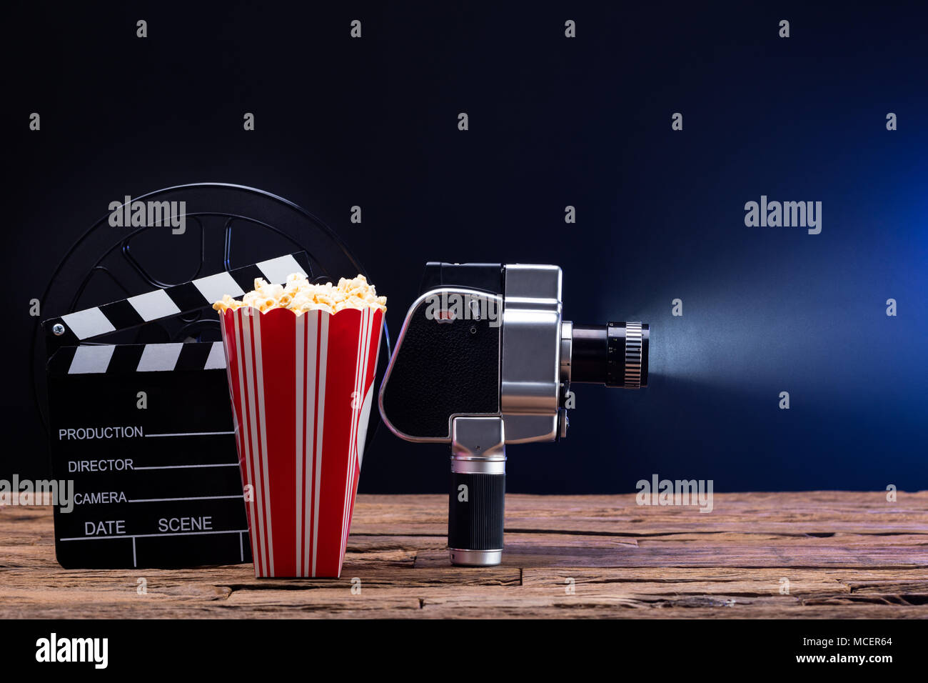 An Illuminated Movie Camera With Popcorn And Clapper Board Against Blue ...