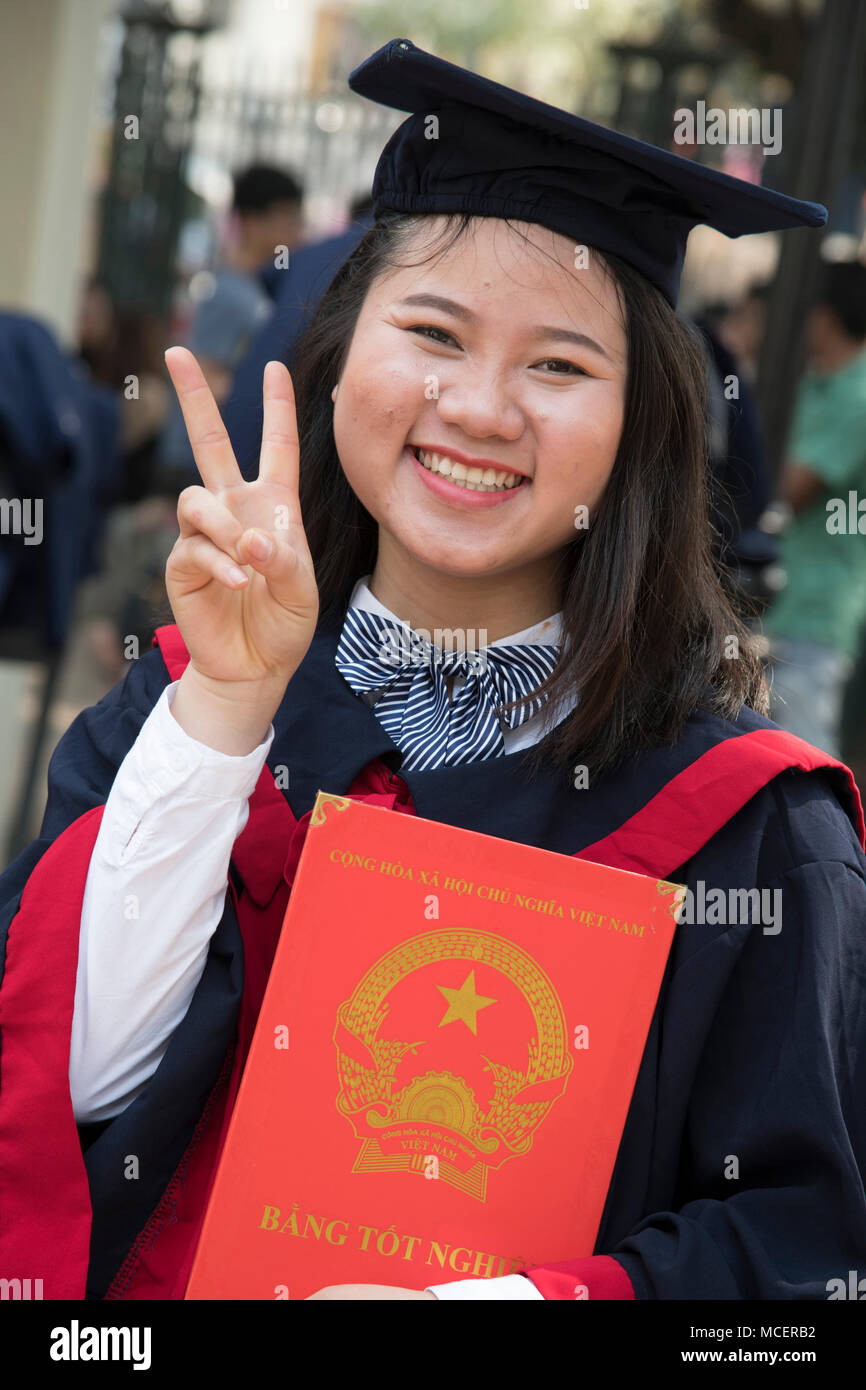 A girl wearing a red and black robe and cap at her graduation ceremony ...