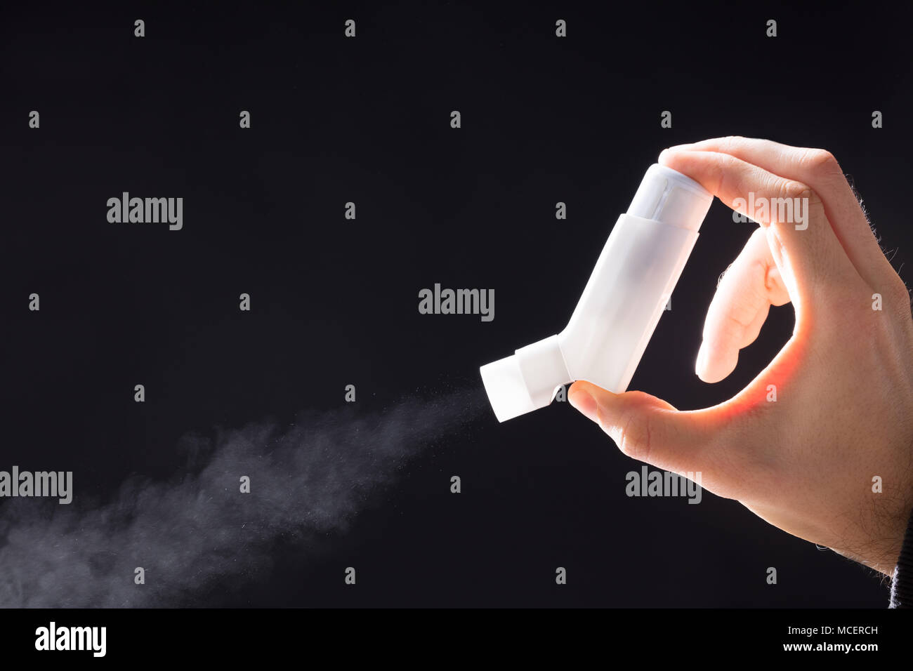 A Person Using Asthma Inhaler On Black Background Stock Photo - Alamy