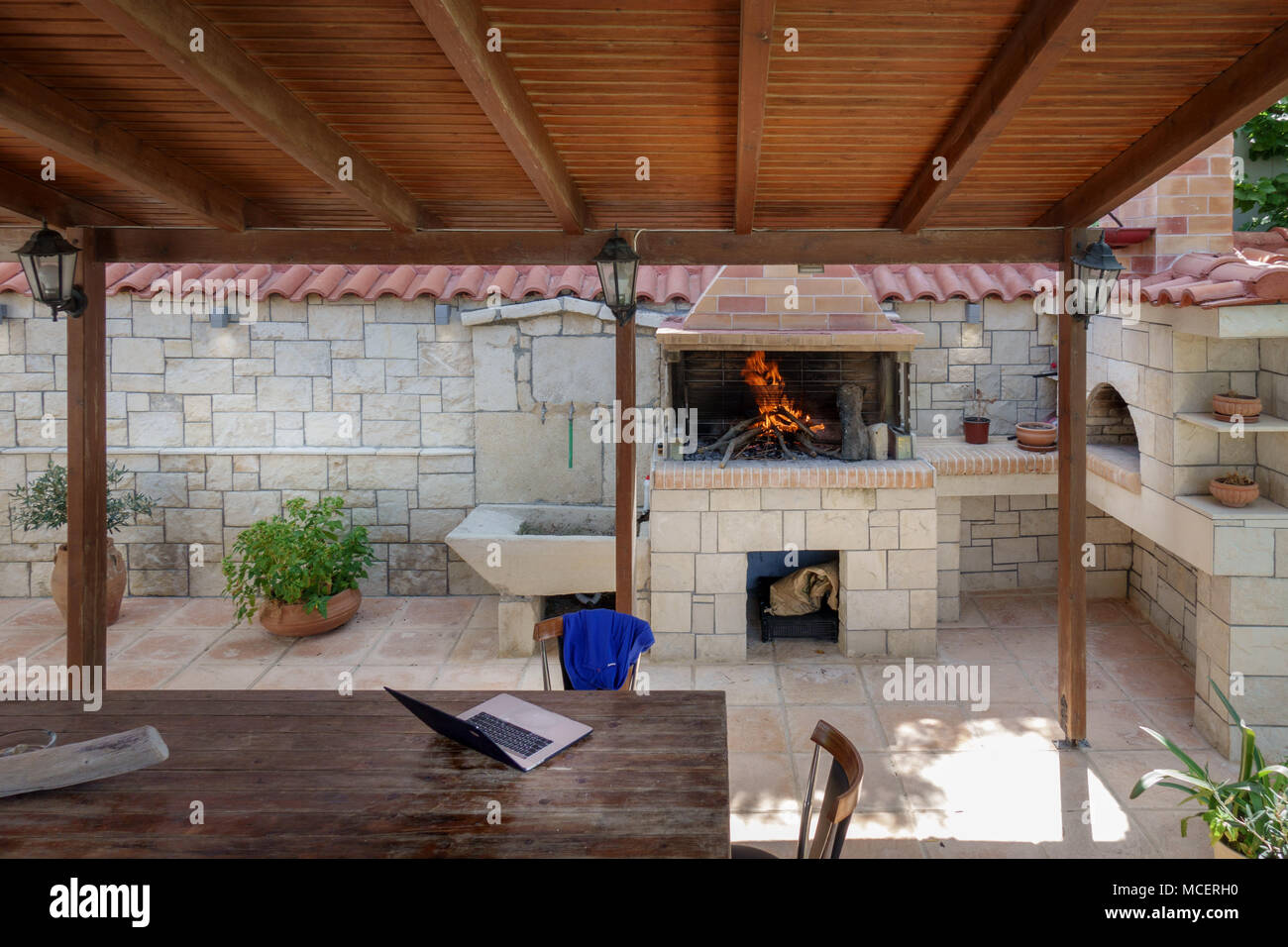 Laptop on wooden table by outdoor burning fireplace Stock Photo - Alamy