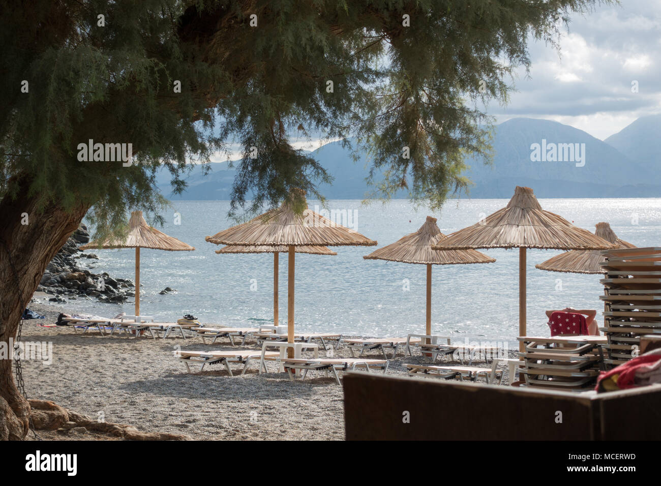 Thatched beach canopies and mountain in Nikos Agiolaos, Crete, Greece ...