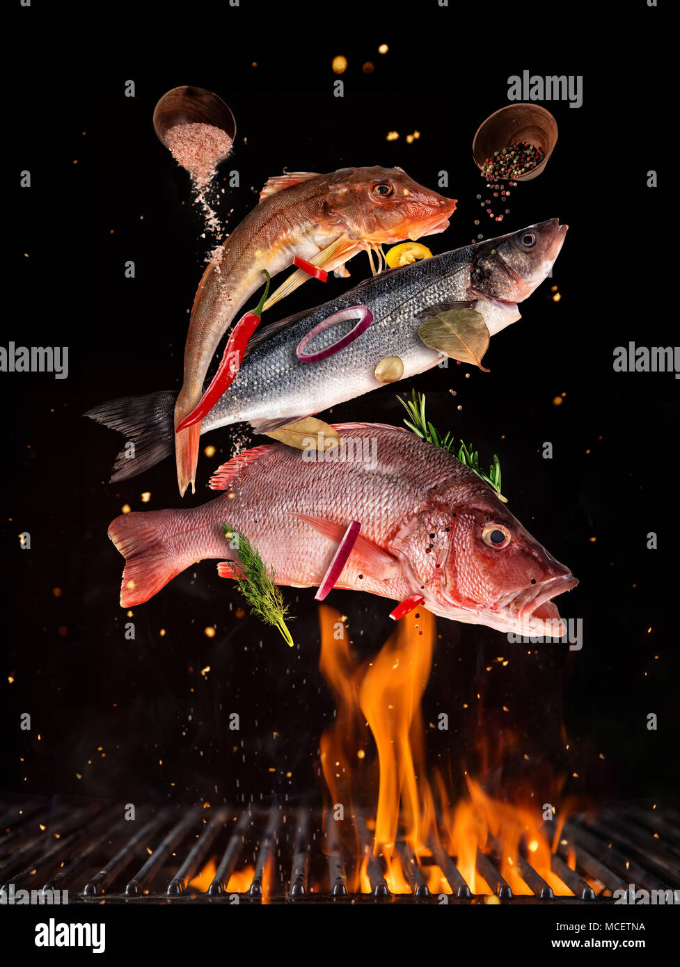Flying raw whole fish from grill grid, isolated on black background ...