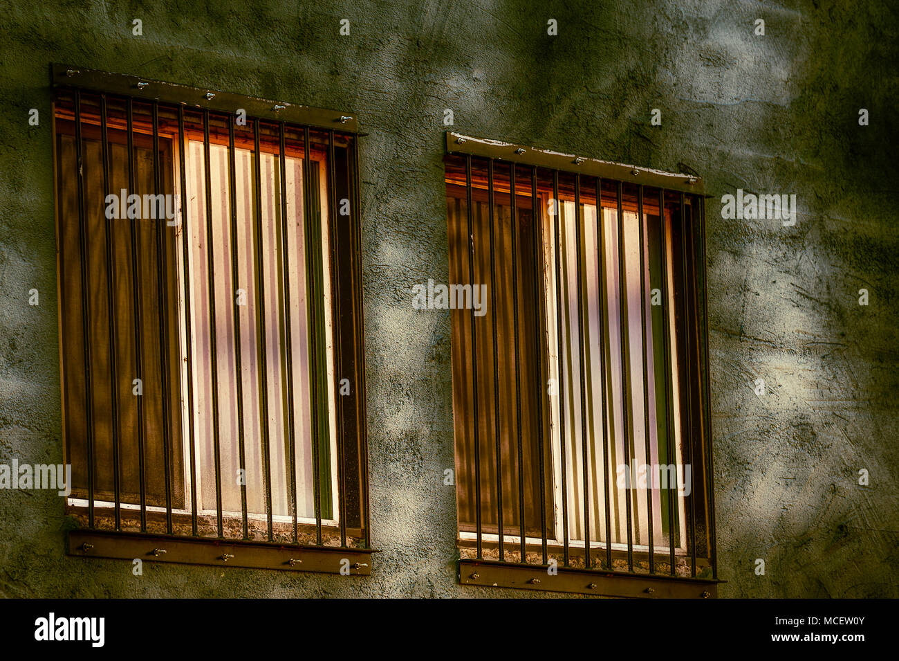 Barded windows reflecting filtered sunlight from a nearby tree not seen ...