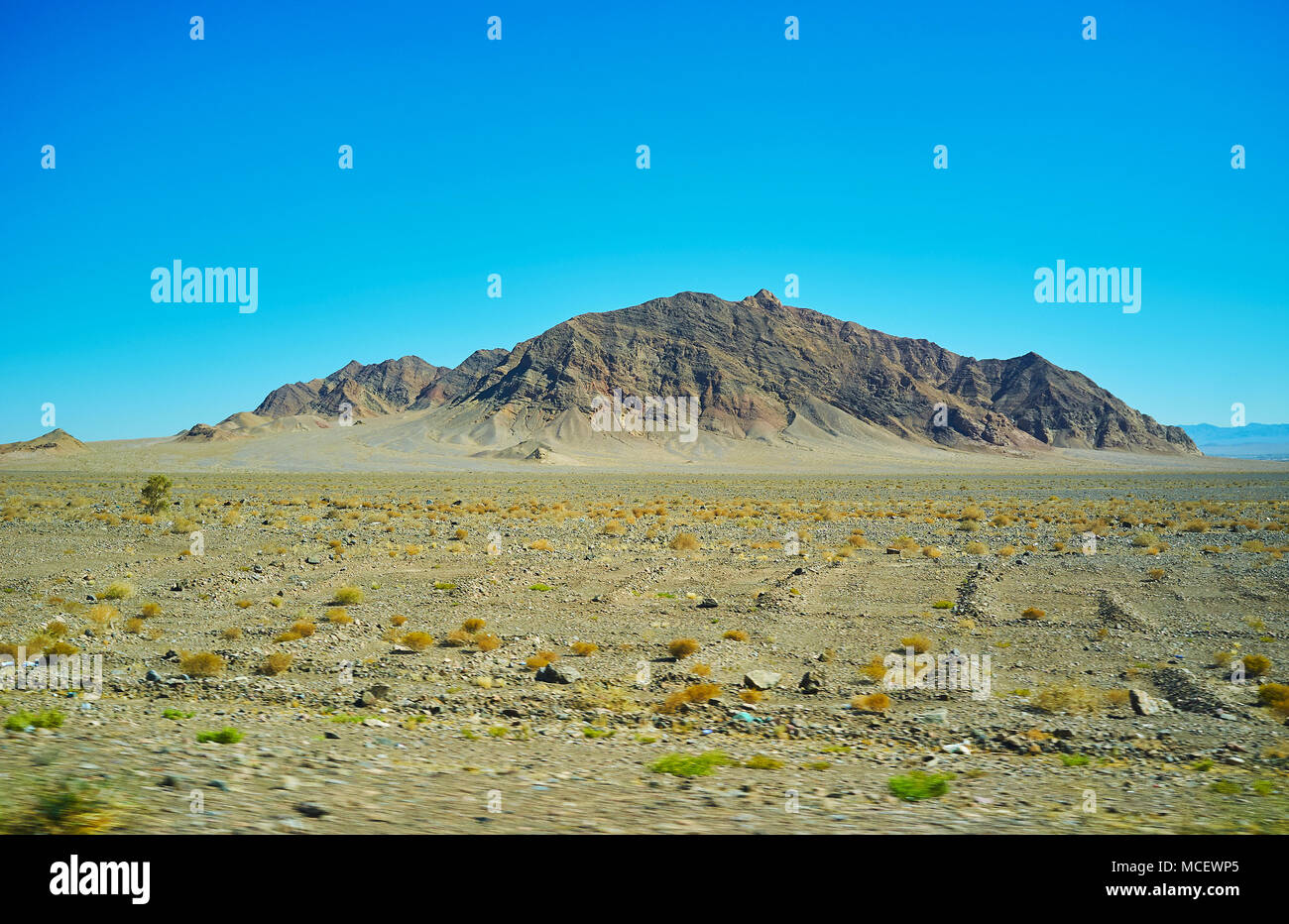 The desert landscape with grey rocky hill and poor vegetation on dry ...