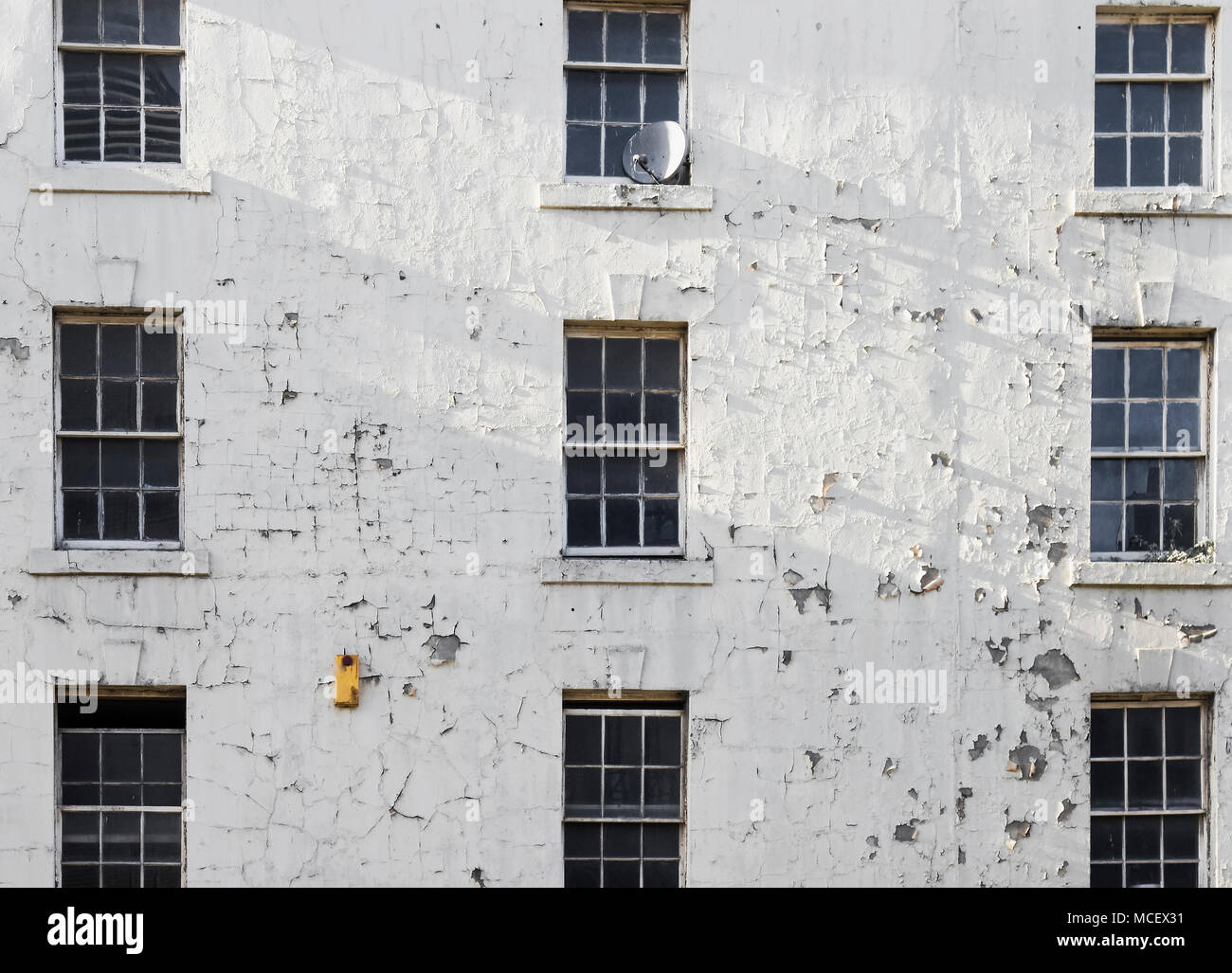 An old whitewashed building with flaking paint on the wall and window ...