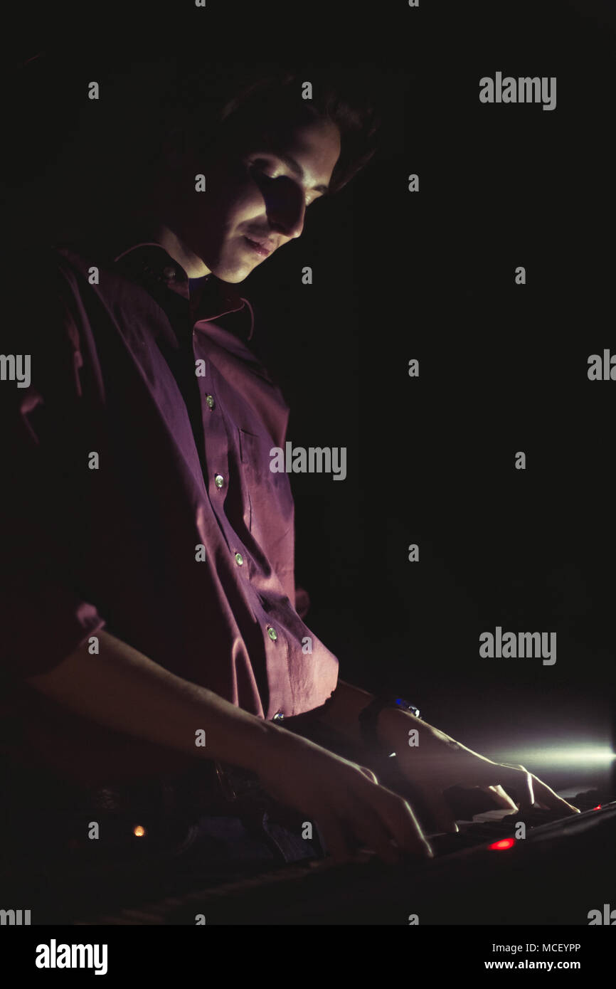 Guy playing on synthesizer keyboard on black background Stock Photo - Alamy