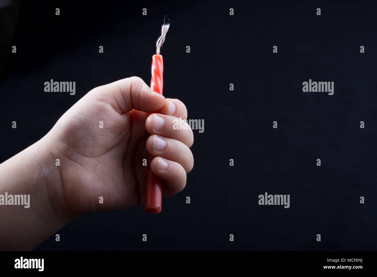 Colorful candle in hand on black background Stock Photo - Alamy