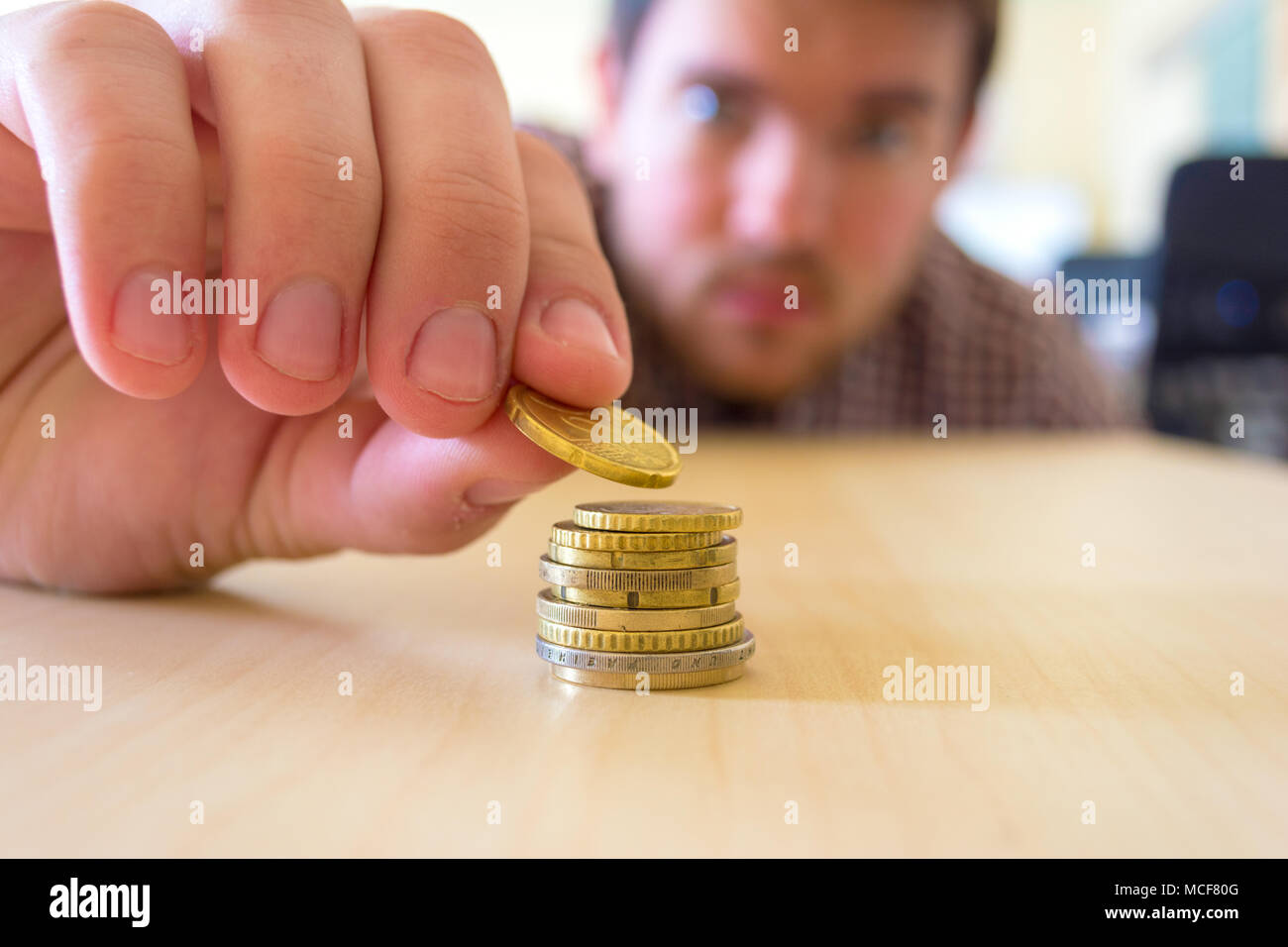 A man counts his coins on a table. The men's hands are gently putting ...