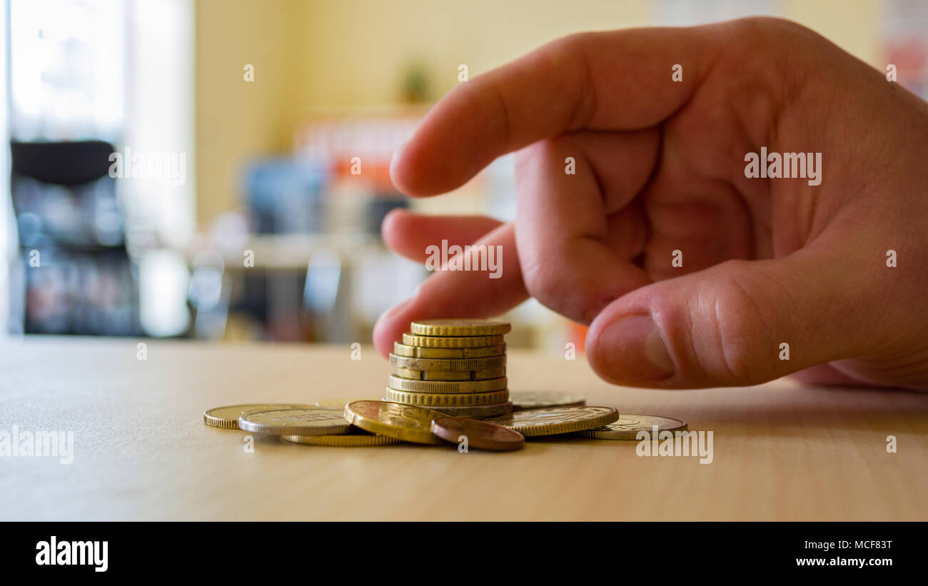 A person uses his fingers to flick a coin stack. The stack made of ne ...