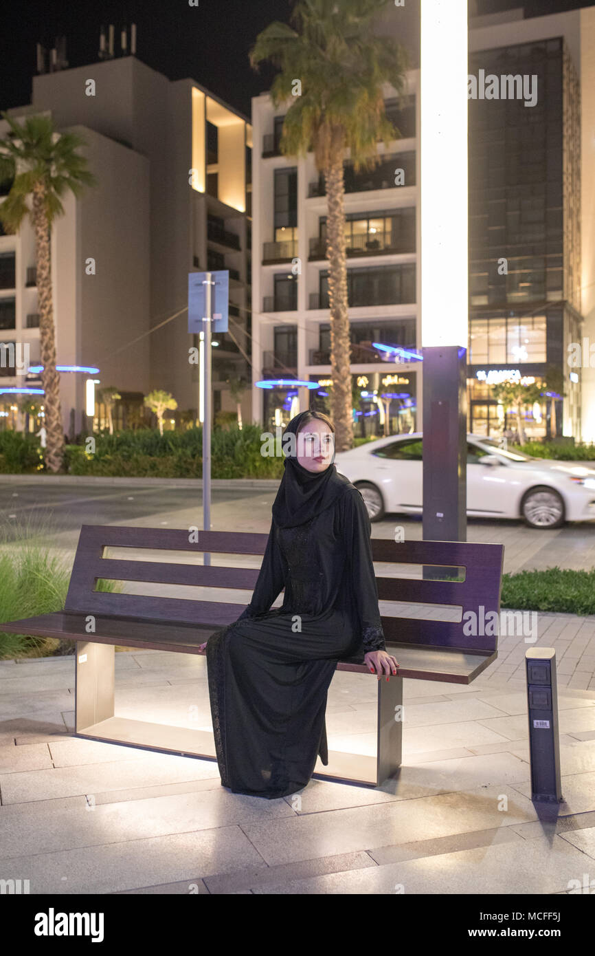 Muslim woman wearing in a hijab sits on a bench in the city Stock Photo ...