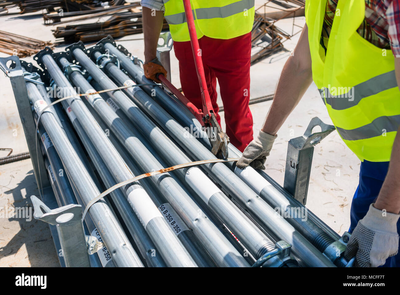 Two efficient blue-collar employees building a metallic scaffolding ...